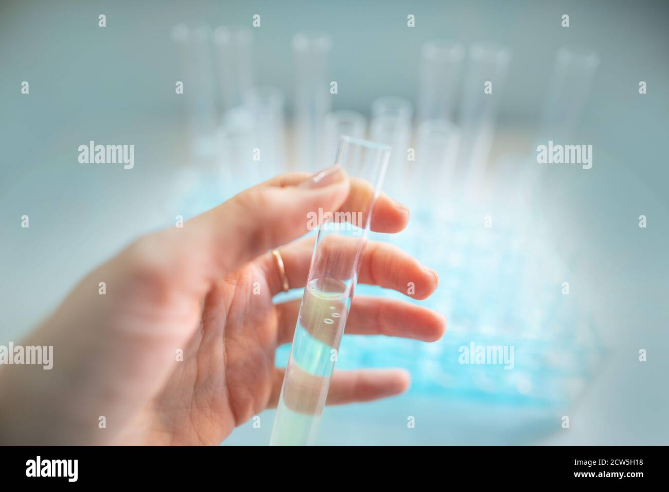 Test tubes are seen through protective goggles in a biology lab, hand ...