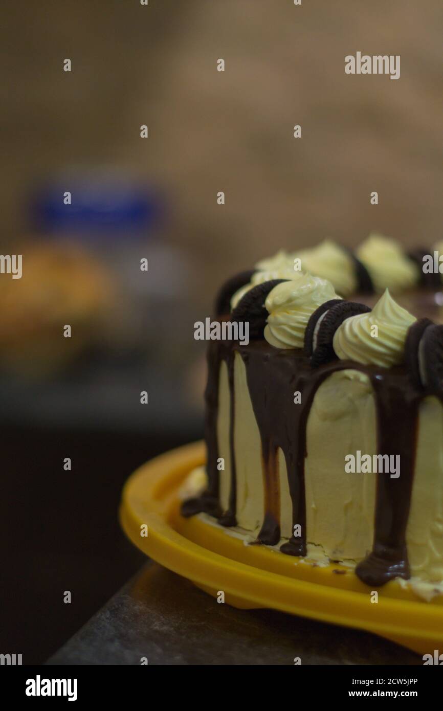 Vertical closeup shot of a half white cake with chocolate sauce and a ...