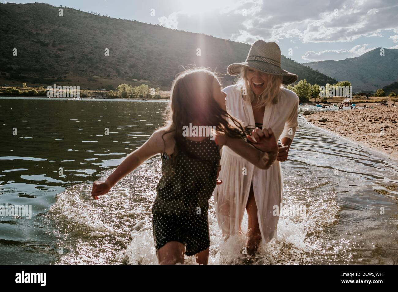 Happy mom chasing young daughter through water Stock Photo - Alamy