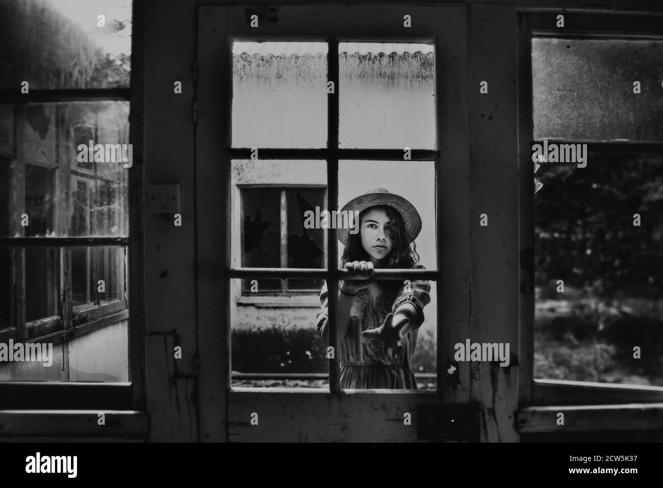 girl reaching out through broken window Stock Photo - Alamy
