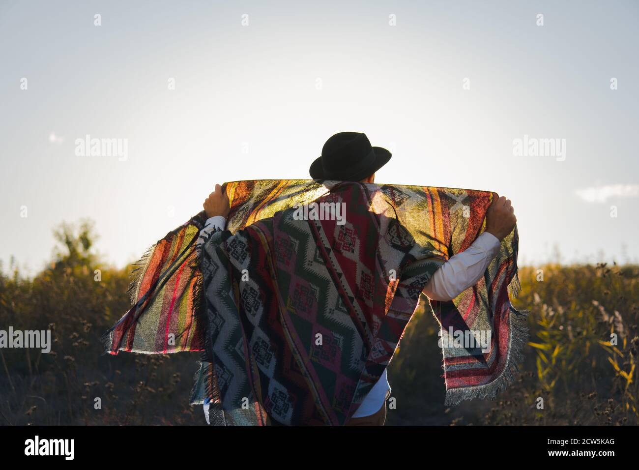 Man standing in a field poses with vintage poncho against the sun Stock ...