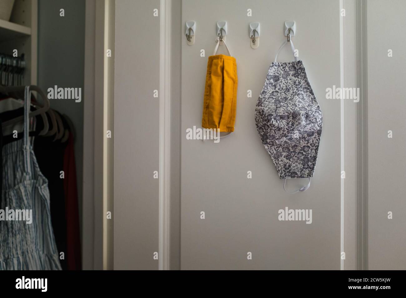 two cloth masks hanging on hooks in closet Stock Photo - Alamy