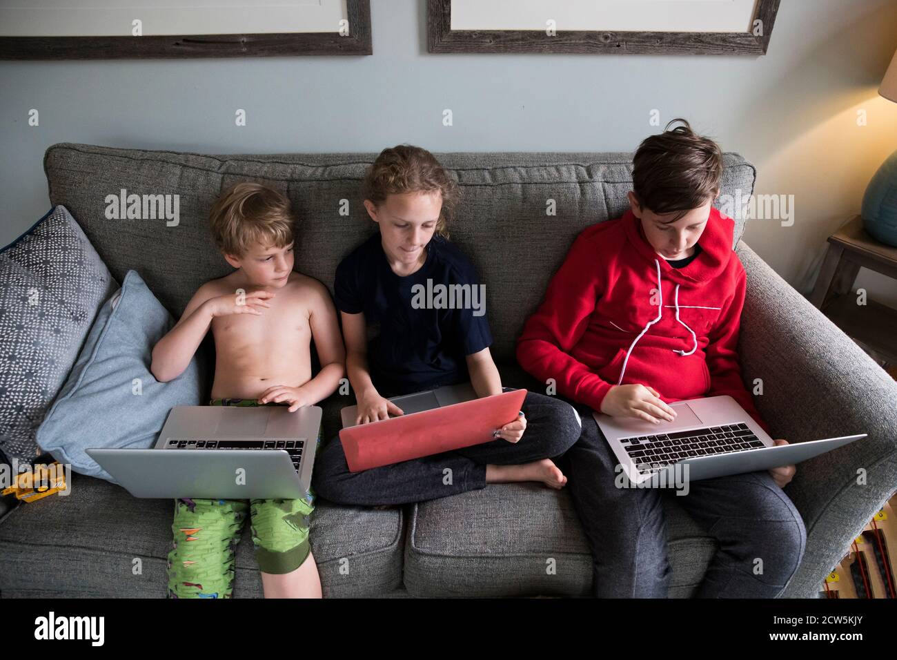 Three Siblings Work on Laptops Together Doing Virtual Learning Stock ...