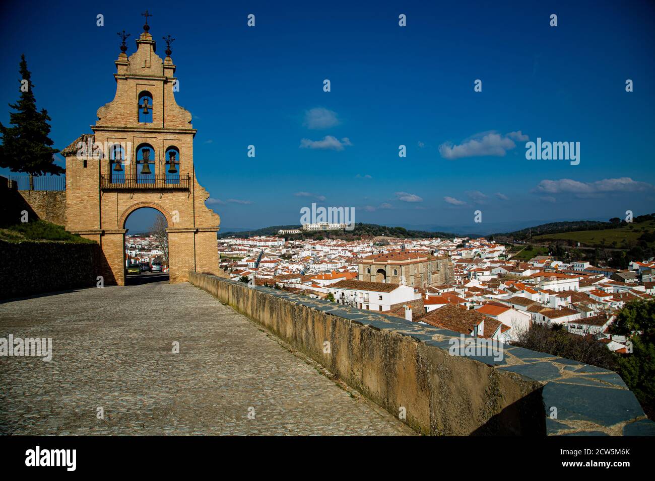 Arch gate with bell tower on the way to hill with village in the backg ...