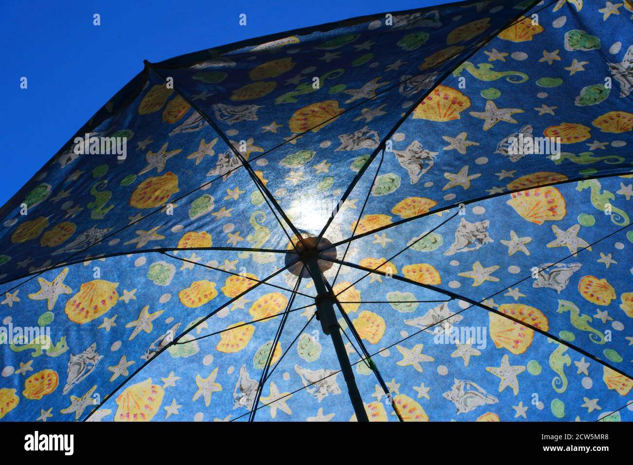 Texture of a open beach umbrella with translucent rays of blue and yel ...