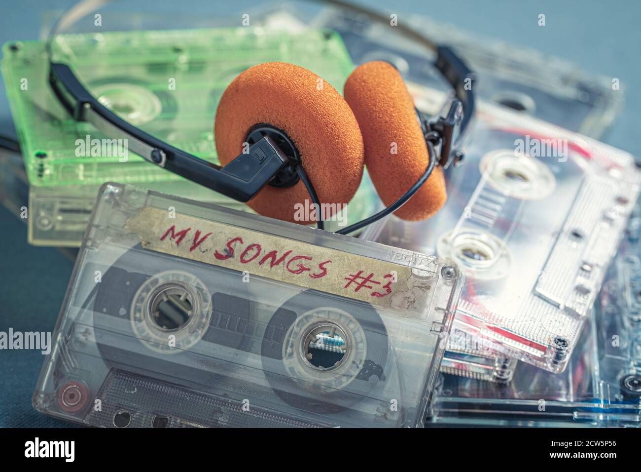 Vintage pile of cassette tapes with orange headphones on blue sofa ...