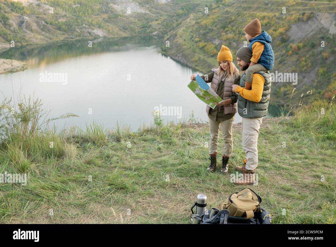 Young family of three looking at map while standing on grass against ...