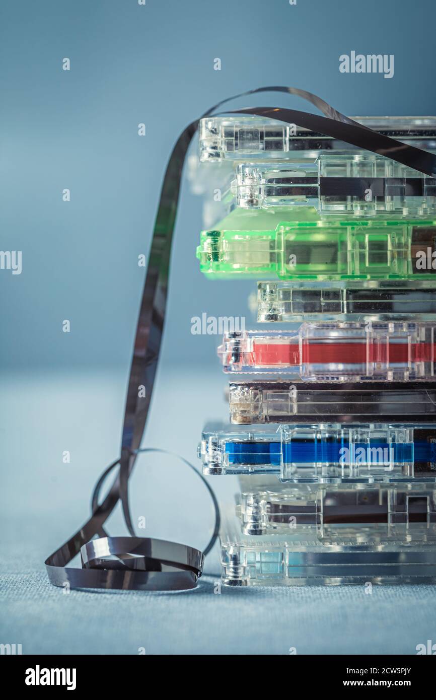 Pile of classic cassette tapes with an extracted tape on blue sofa ...