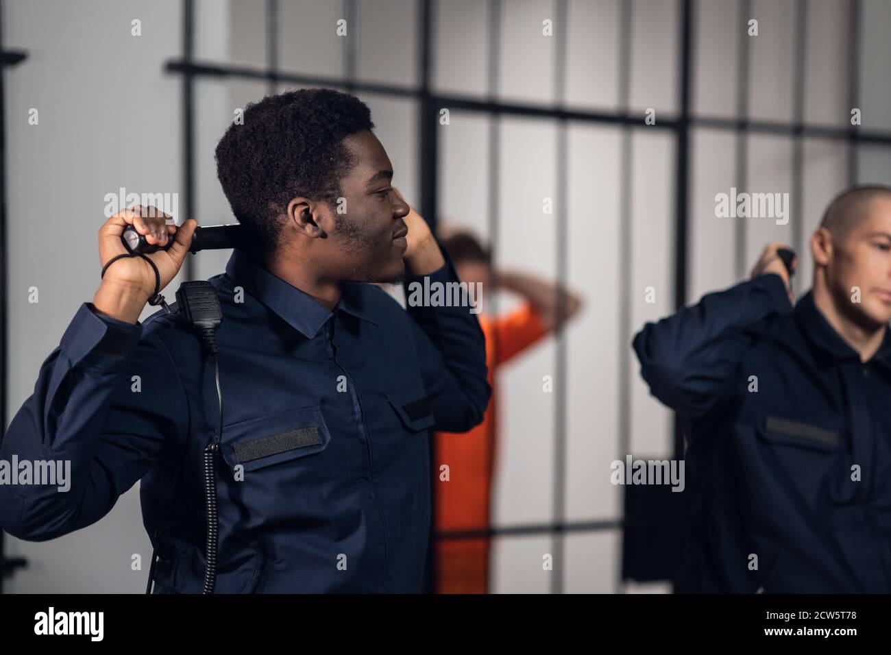 Prison guards smile as they stand with batons near cells with dangerous ...