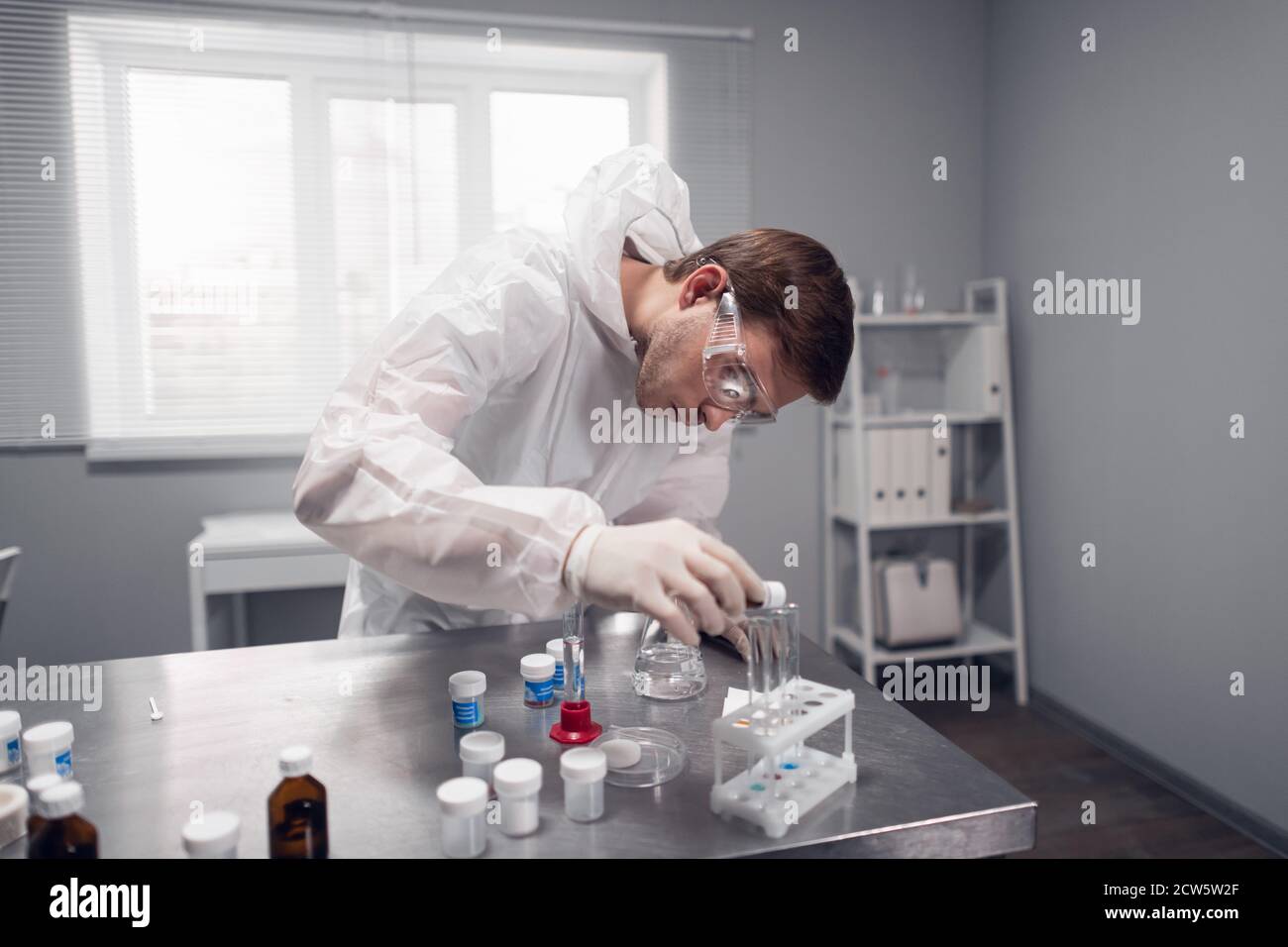 Scientist pouring some chemical product into the test tubes on his ...