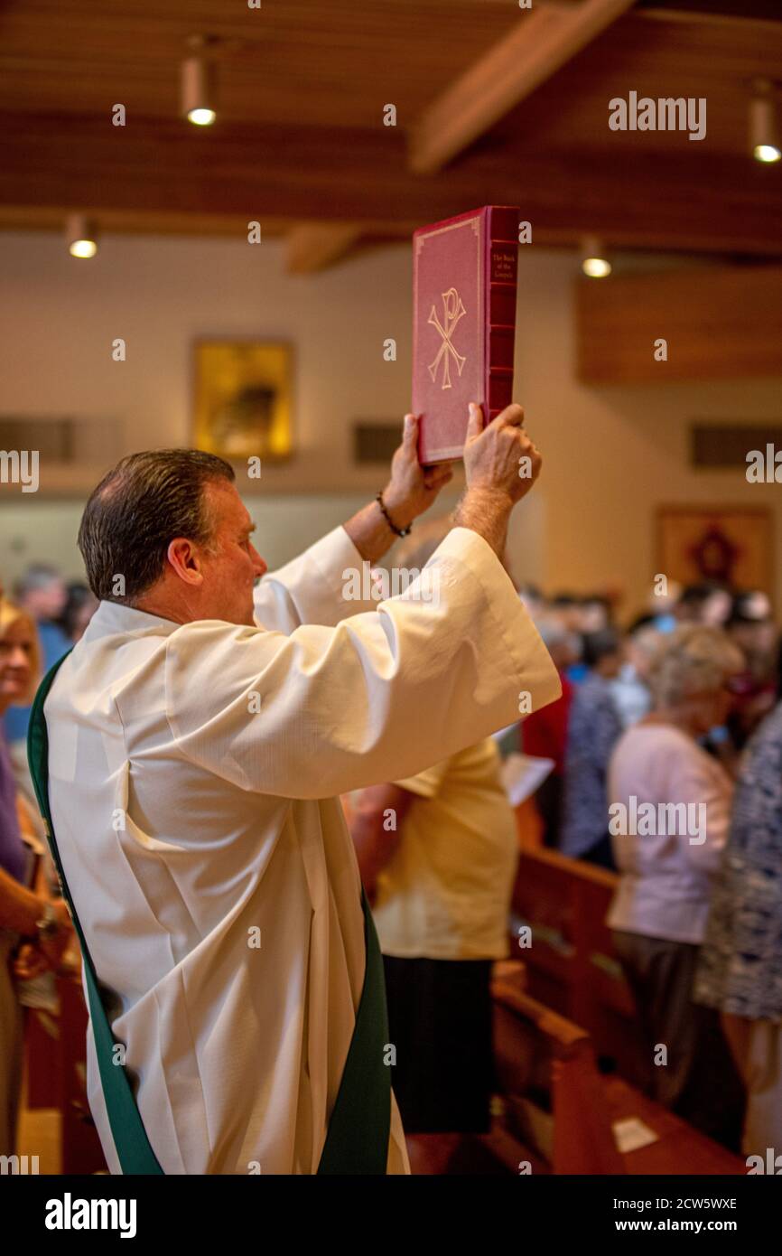 A robed deacon holds a book of scripture while marching in the ...