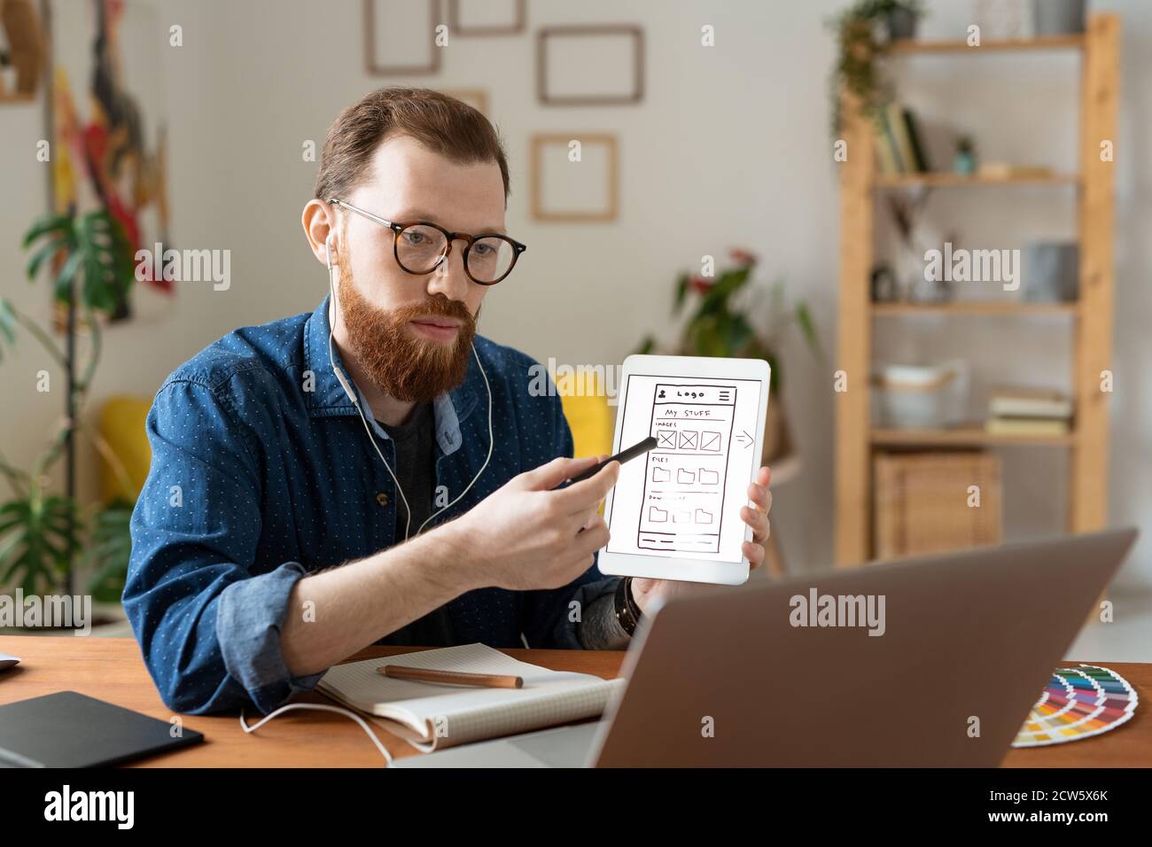 Young serious software developer pointing at sketch of smartphone model ...