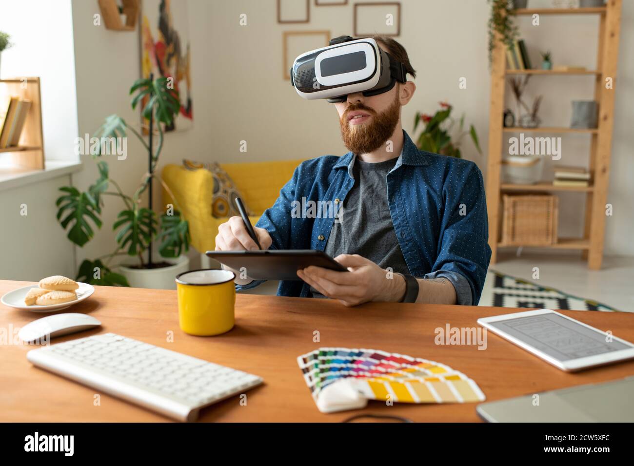 Young contemporary creative designer in vr headset drawing on tablet ...
