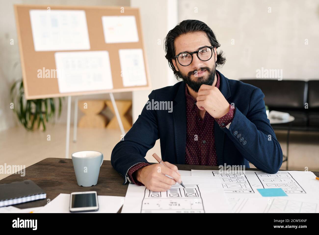 Happy young bearded male developer of mobile applications making new ...