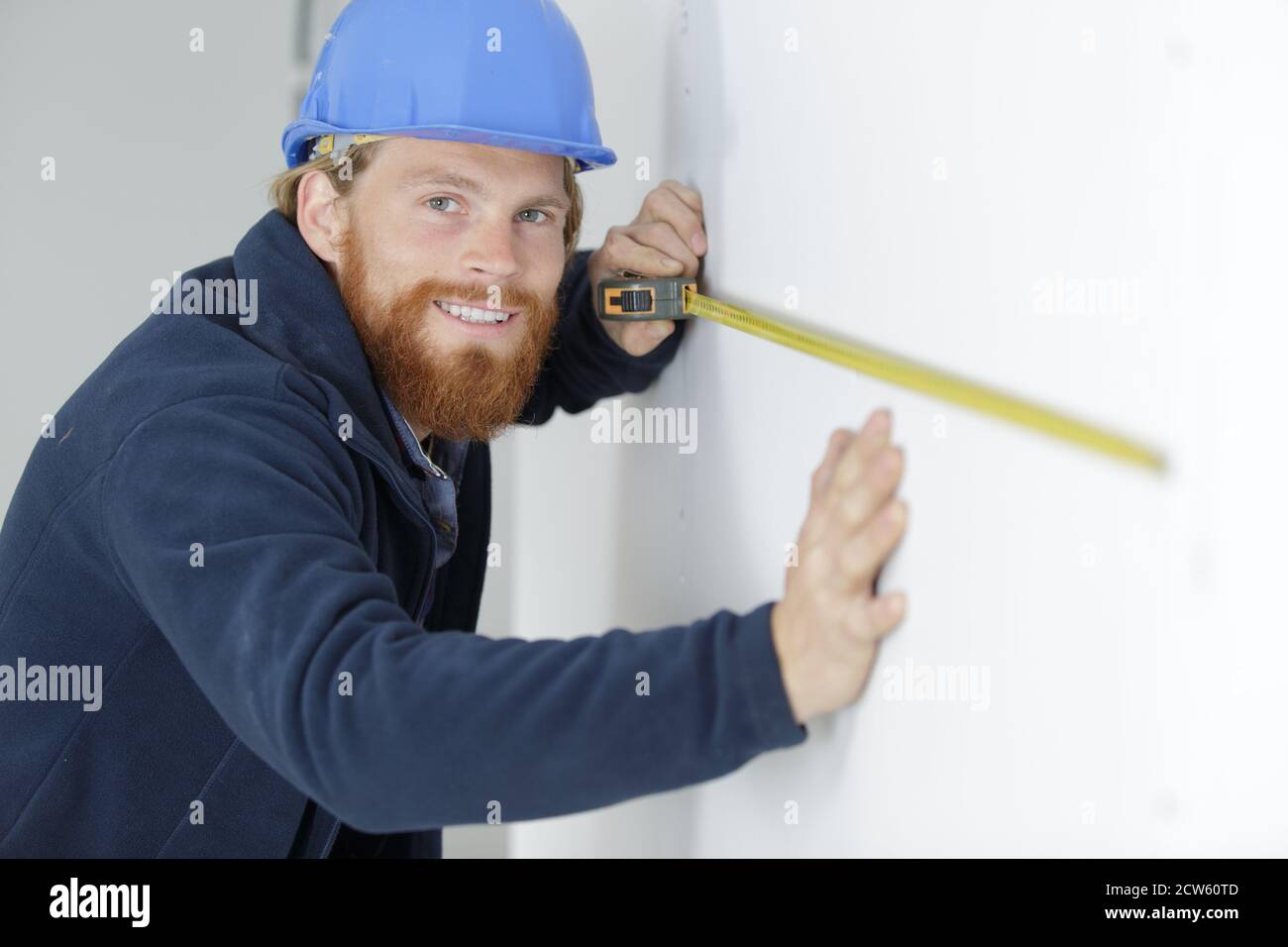 happy man measuring the wall with a measuring tape Stock Photo - Alamy