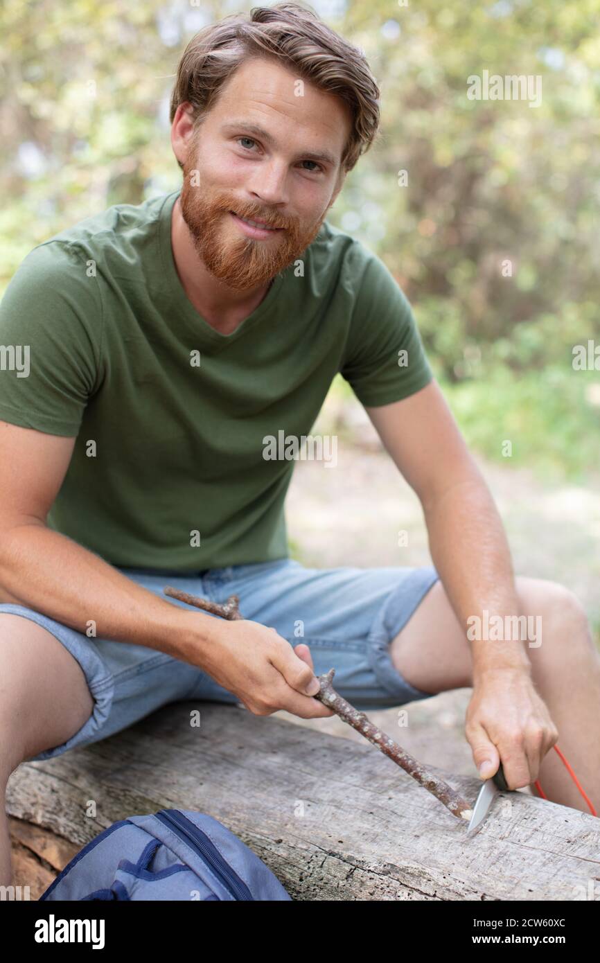 skillful man whittling stick in forest Stock Photo - Alamy