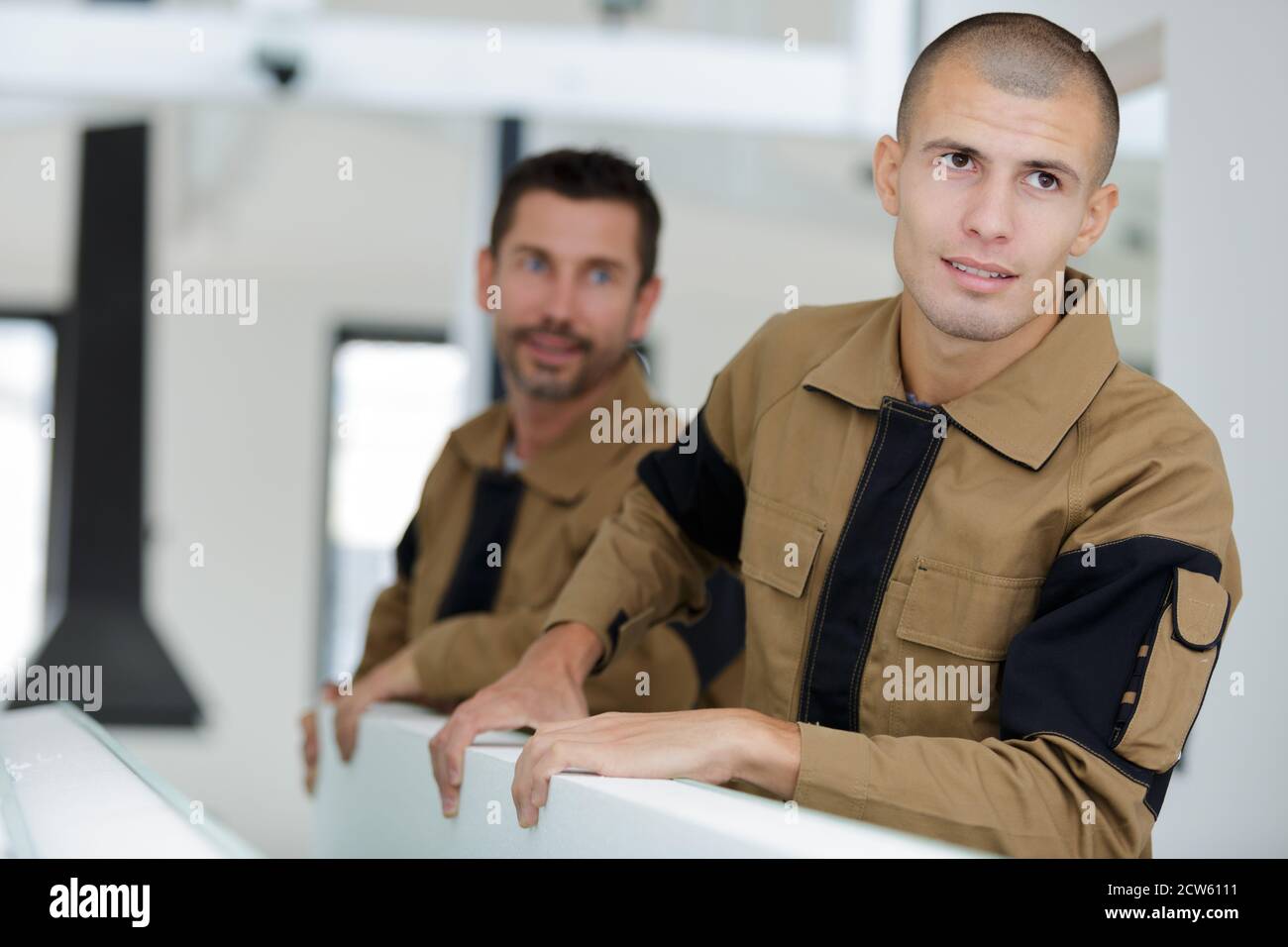 two workers carrying a board Stock Photo - Alamy