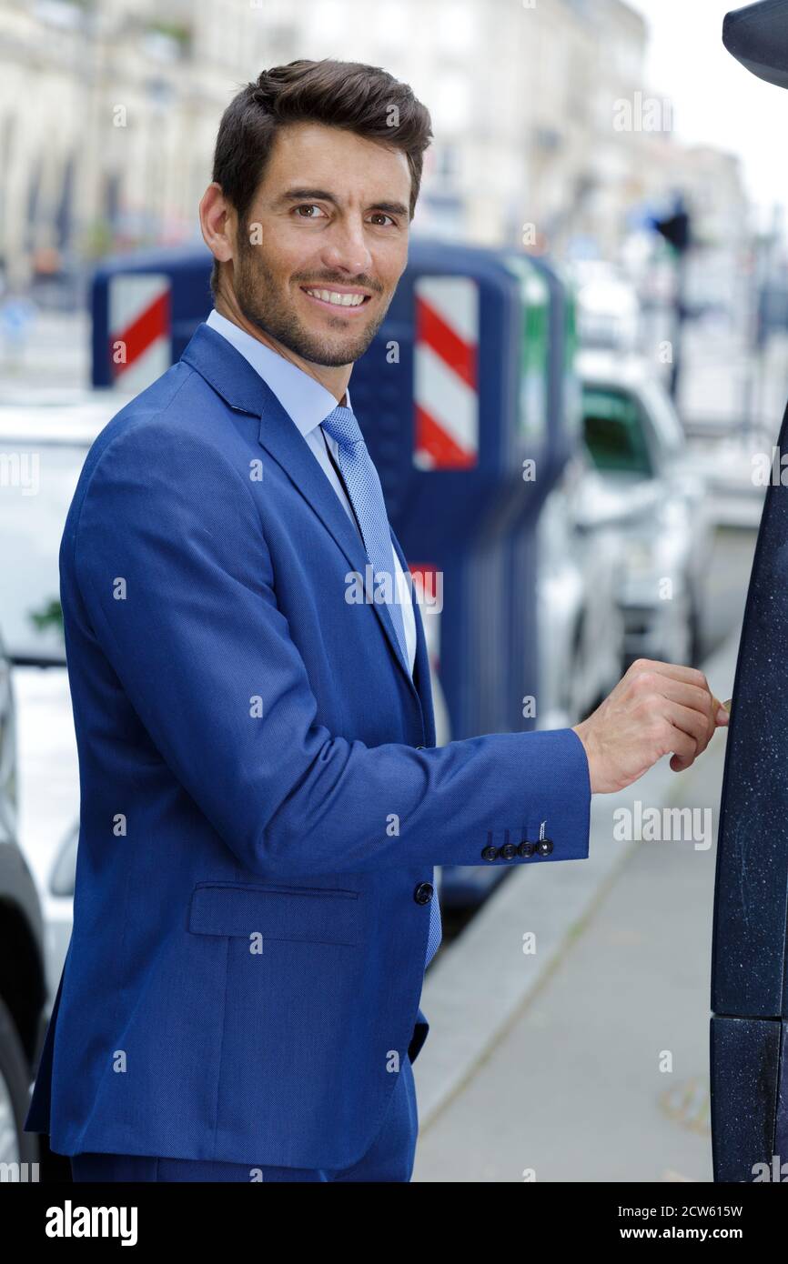 happy young businessman inserting coin into parking machine Stock Photo ...