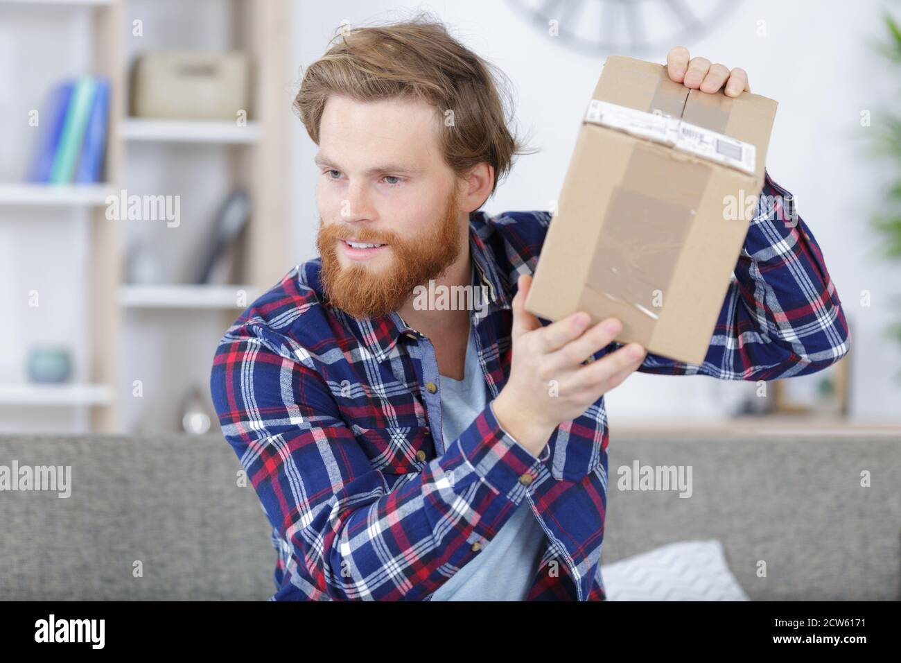 guy shaking cardboard box to guess its contents Stock Photo - Alamy