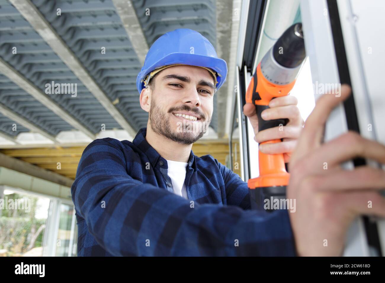 a happy man drilling window frame Stock Photo - Alamy