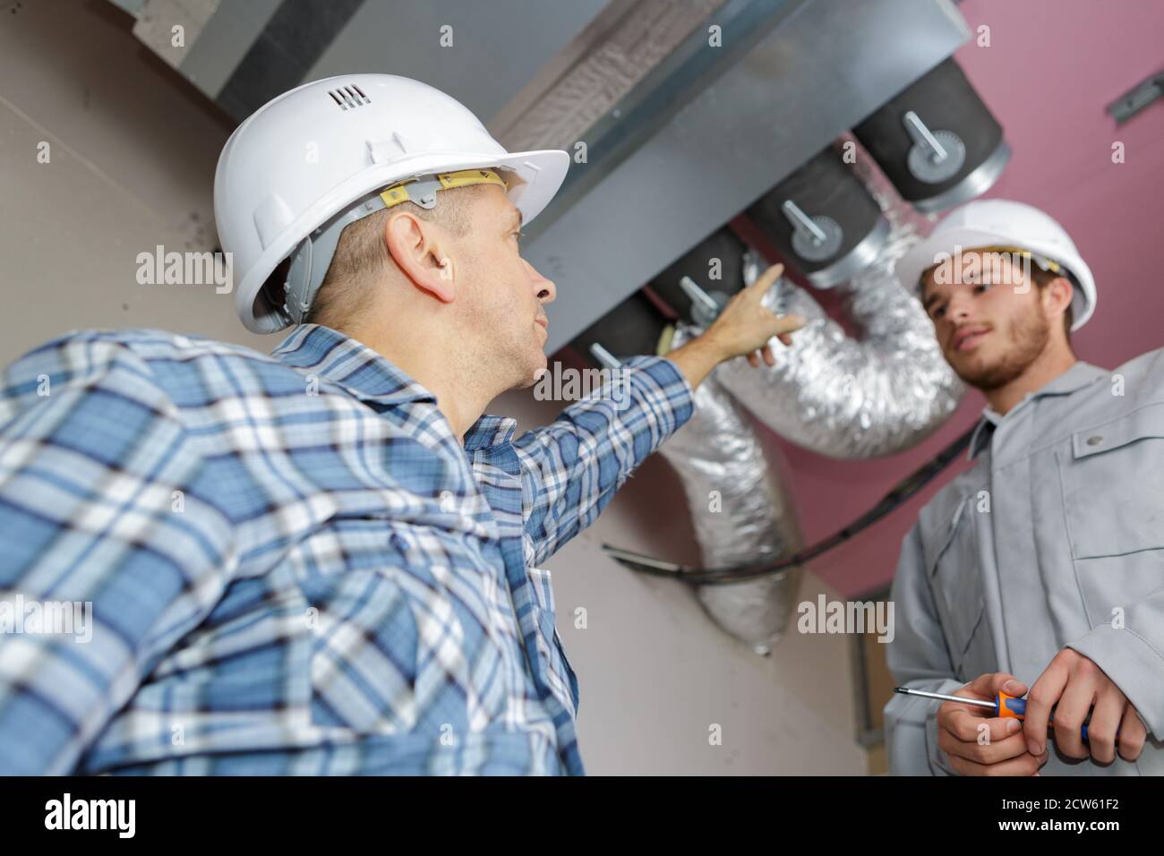worker pointing at air duct installation Stock Photo - Alamy
