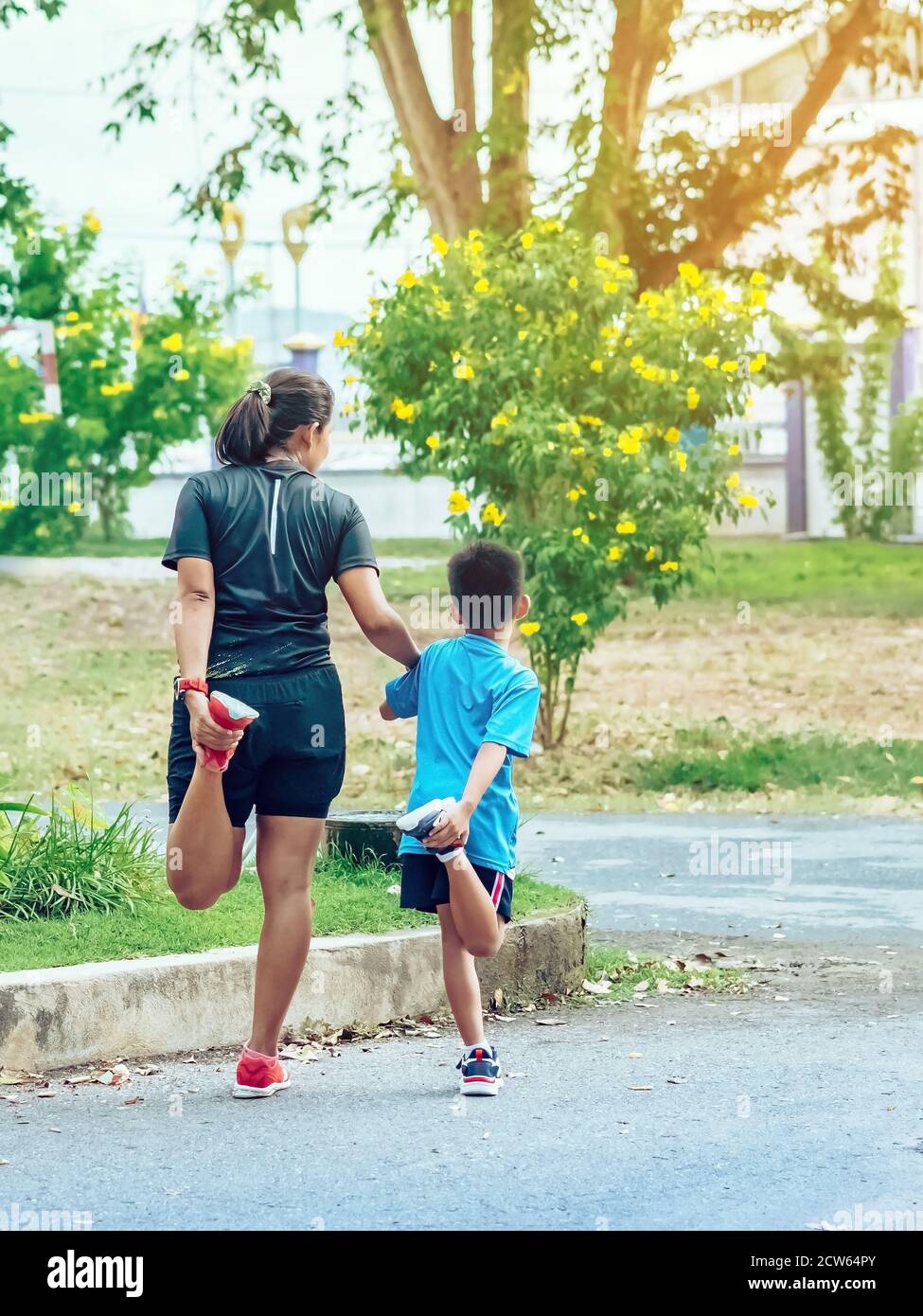 Back view of sportive happy mother training her son doing stretching ...