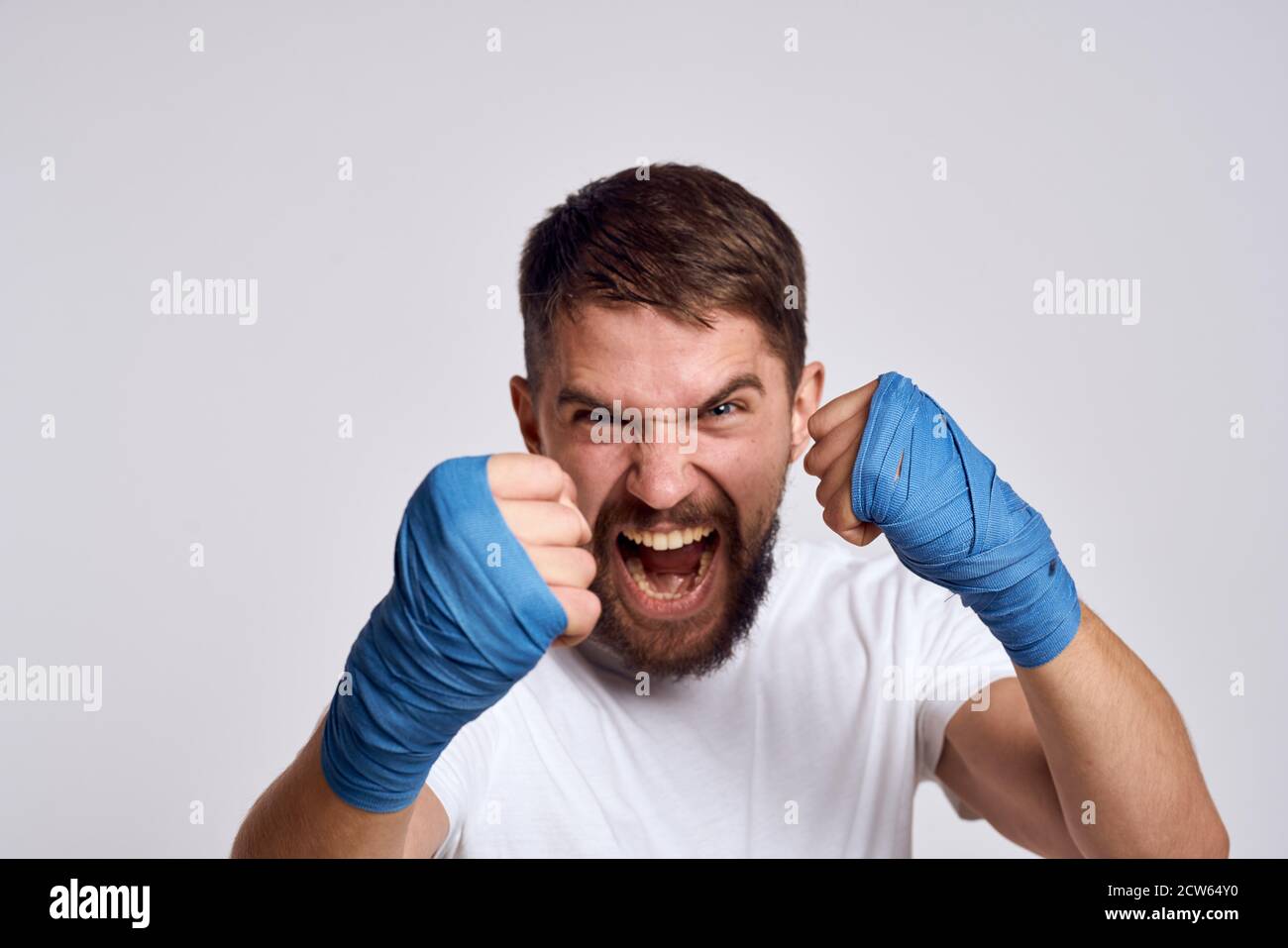 A sportive man in a white T-shirt boxing bandages on his hands ...