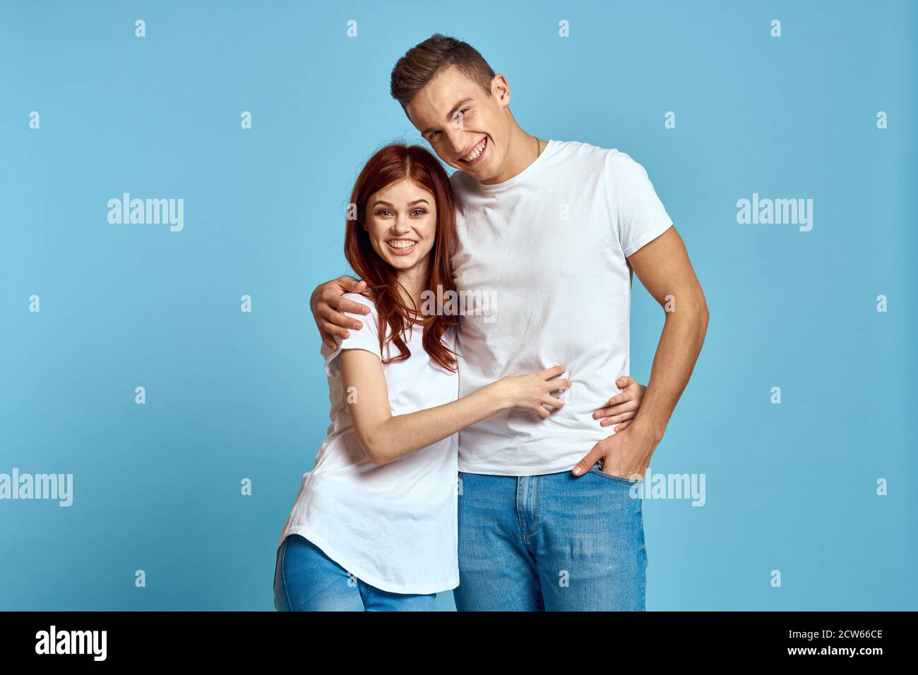 enamored man and woman in jeans and a T-shirt on a blue background hug ...
