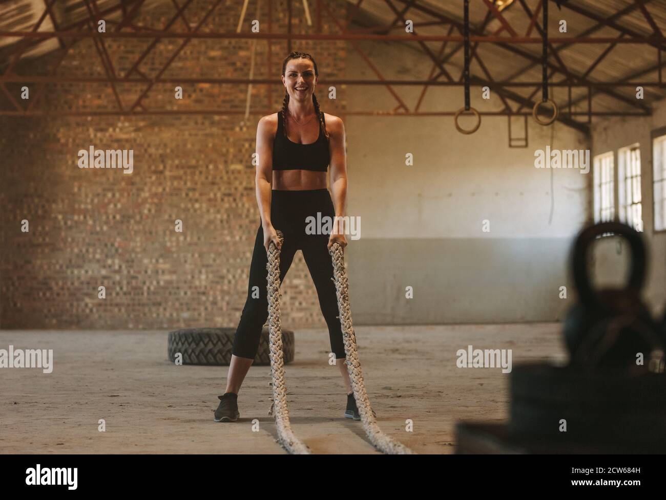 Female athlete about to start battling rope workout. Woman working out ...