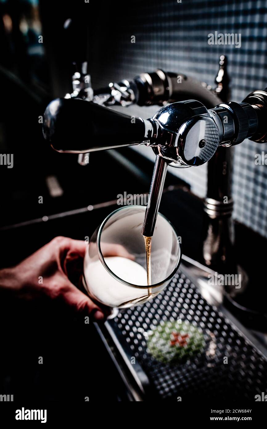 Vertical shot of a barista's hand with glass and pouring coffee using ...