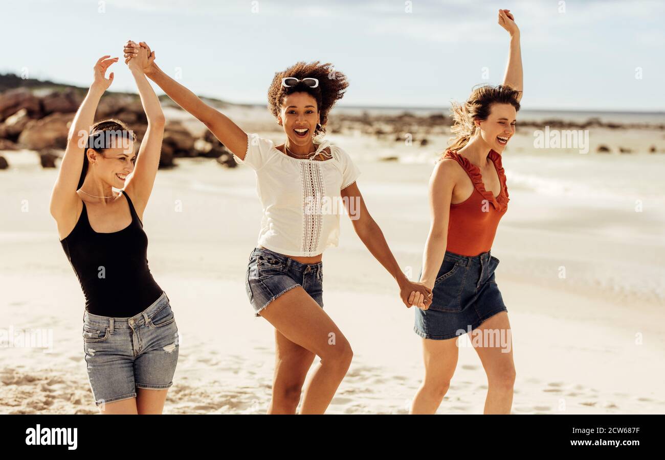 Young women walking on beach in a playful mood. Multiethnic women ...