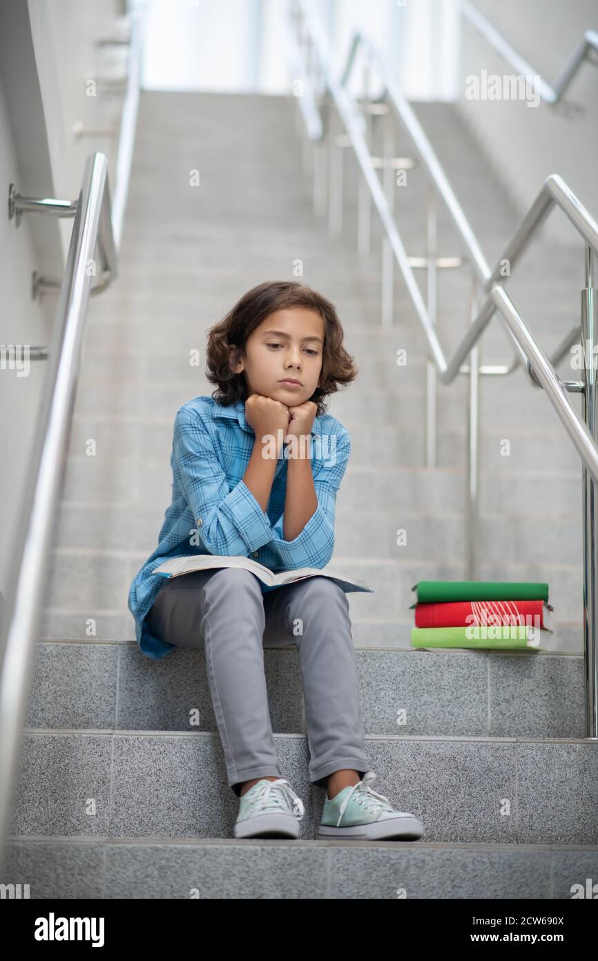 Sad boy sitting on steps of city stairs Stock Photo - Alamy