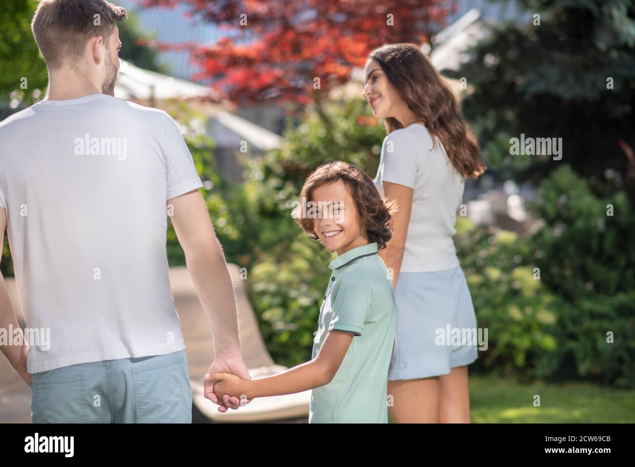 Parents back and son turning his head to camera Stock Photo - Alamy