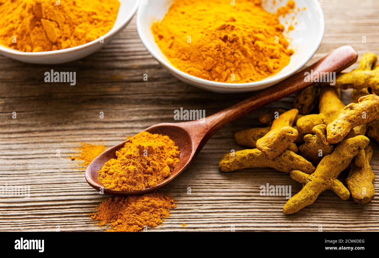 Yellow turmeric powder and dry roots on wooden background Stock Photo ...