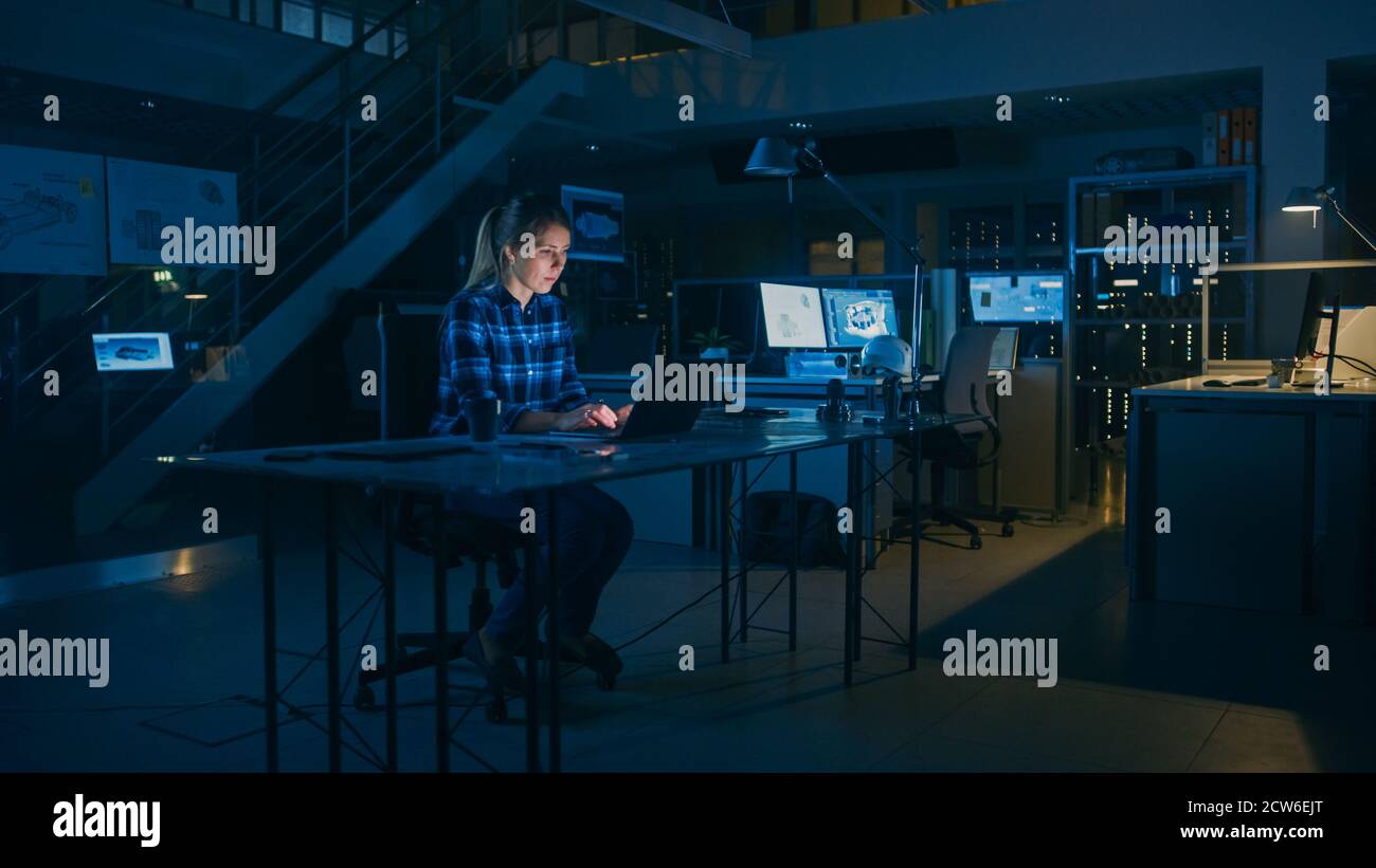 Beautiful Female Engineer Sitting at Her Desk Works on a Laptop ...