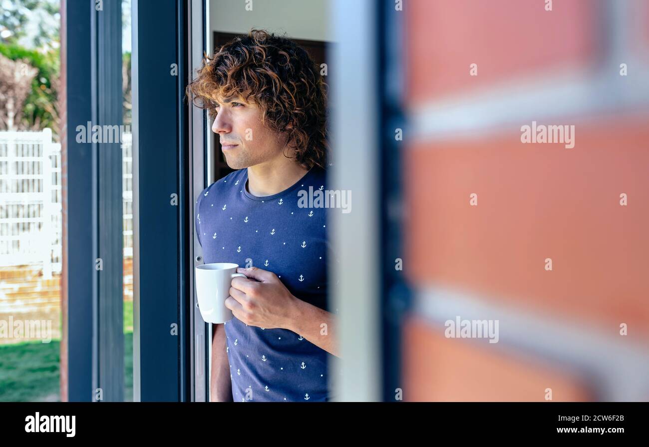Man drinking coffee leaning against the window frame Stock Photo - Alamy