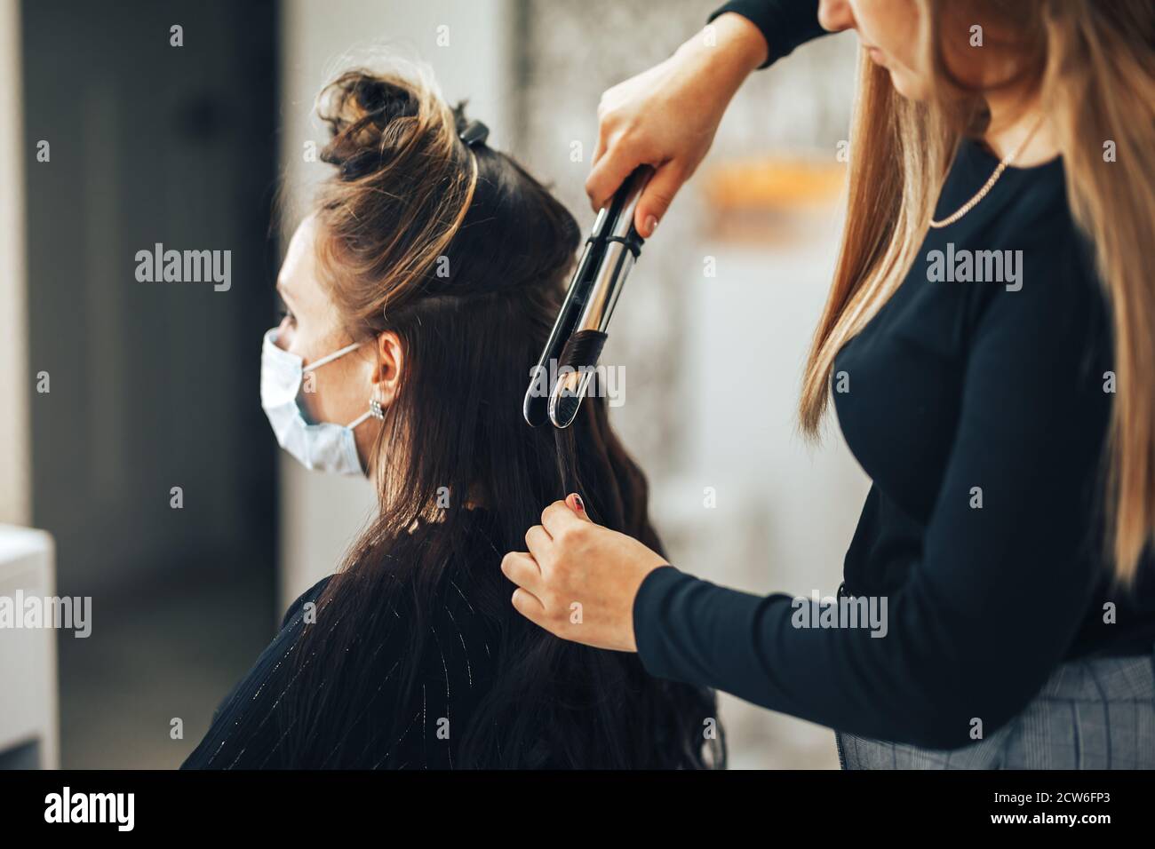 Woman in medical mask gets her hair done in beauty salon during ...