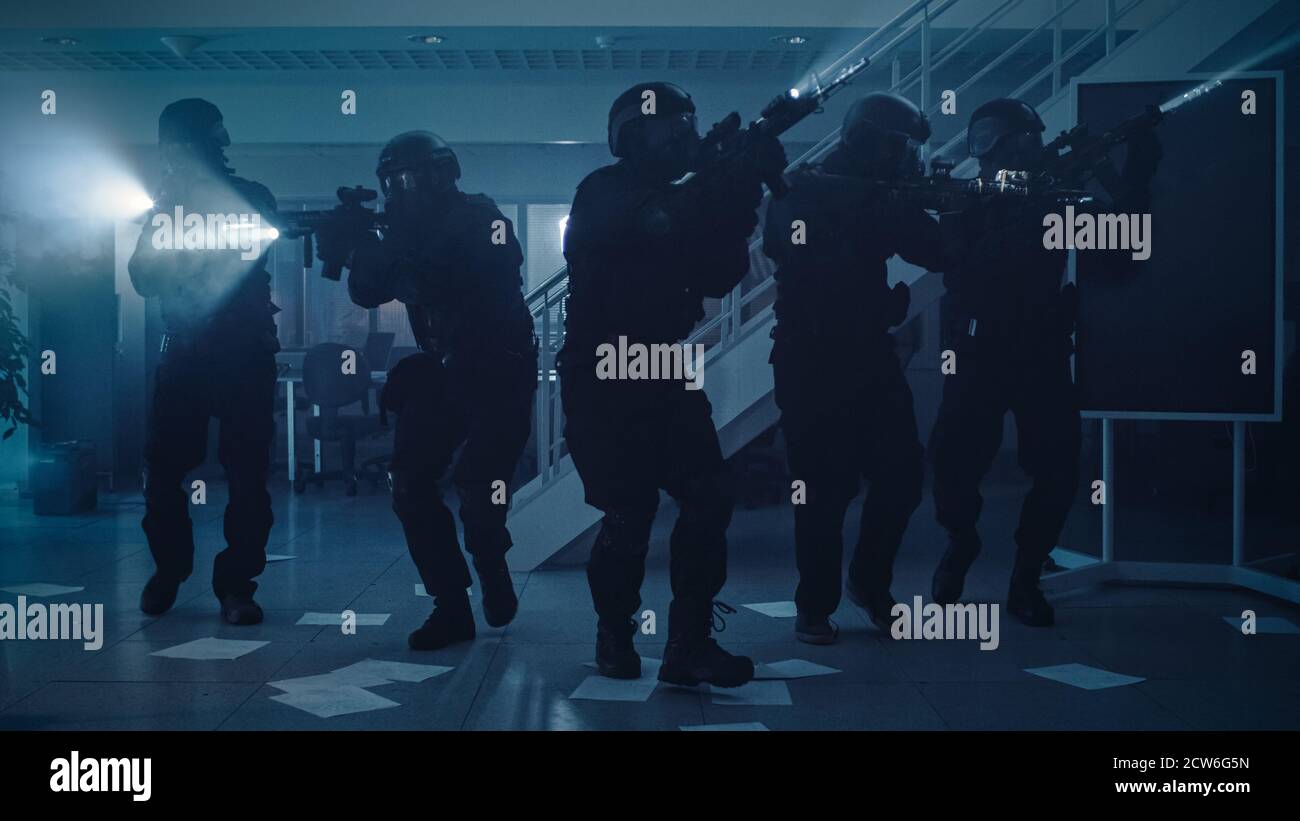 Masked Team of Armed SWAT Police Officers Move in a Hall of a Dark ...
