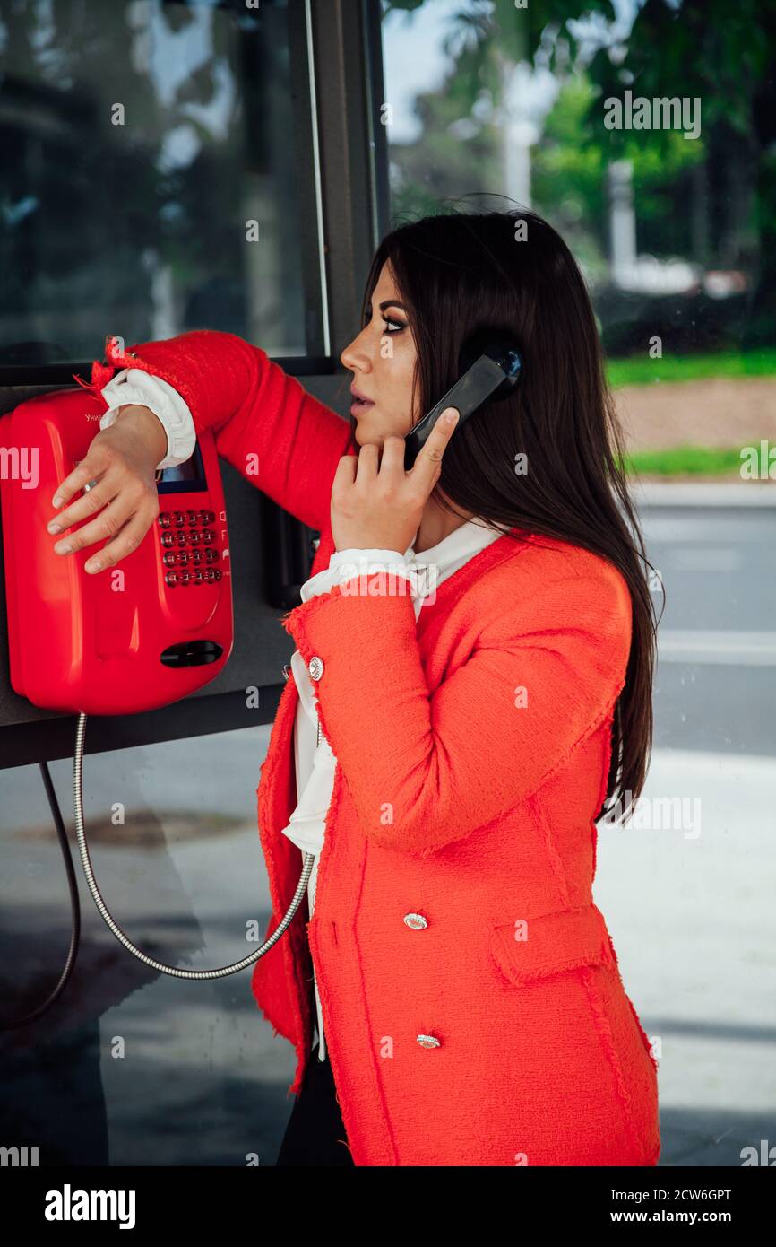 Beautiful woman in red talking on street phone in a phone booth Stock ...