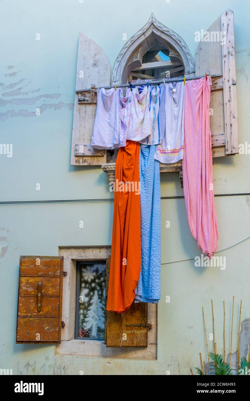 Freshly washed clothes drying on a old Venetian style window in ...