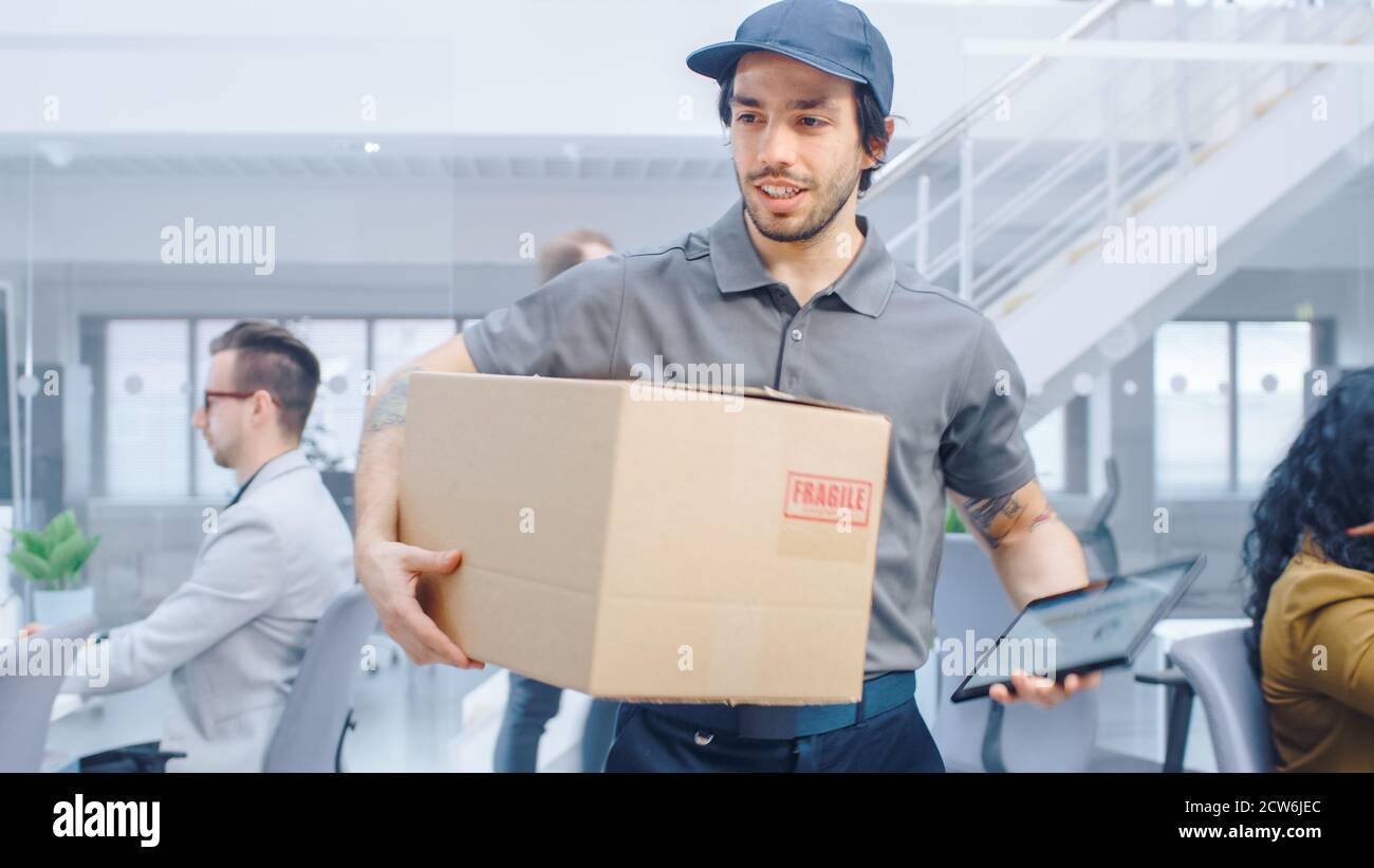 Happy Delivery Man Wals in Corporate Office with Tablet Computer and ...