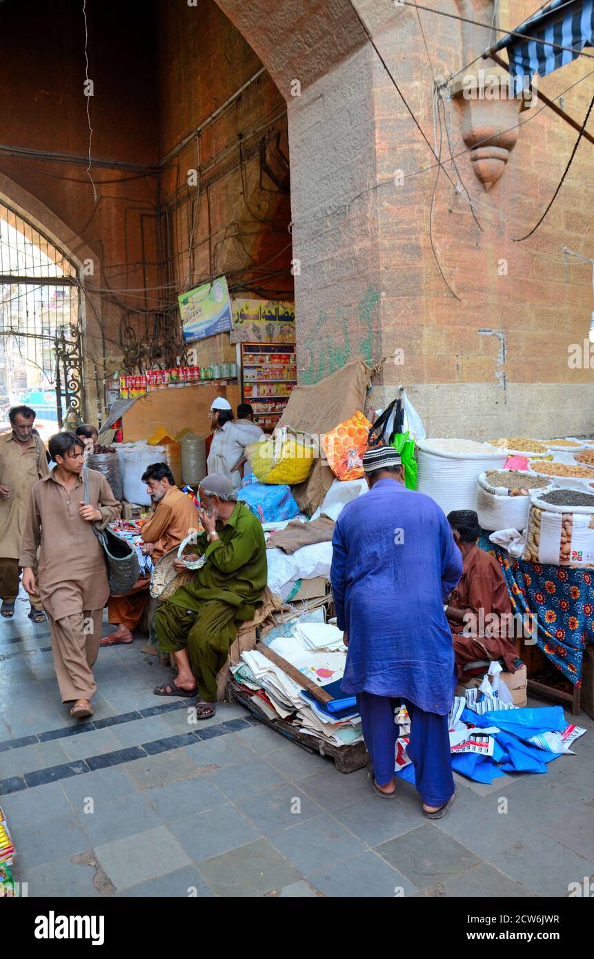 Men and coolies mill around arched entrance to Empress Market shops ...
