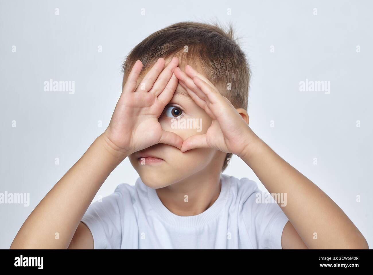 little boy looks forward through the frame from the fingers Stock Photo ...