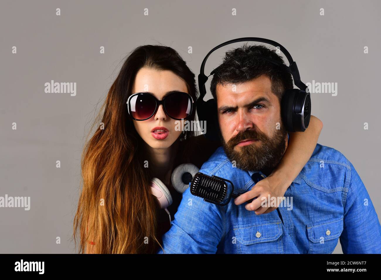 Couple in love wears headphones and holds microphone. Man with beard ...