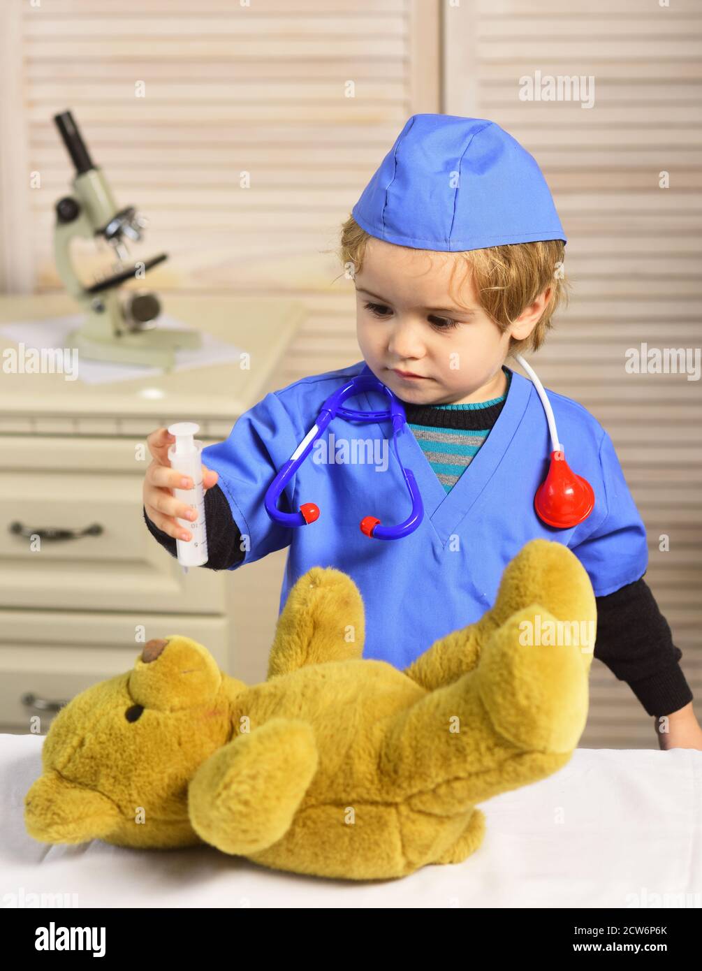 Boy in surgical uniform holds syringe on wooden background. Medical ...