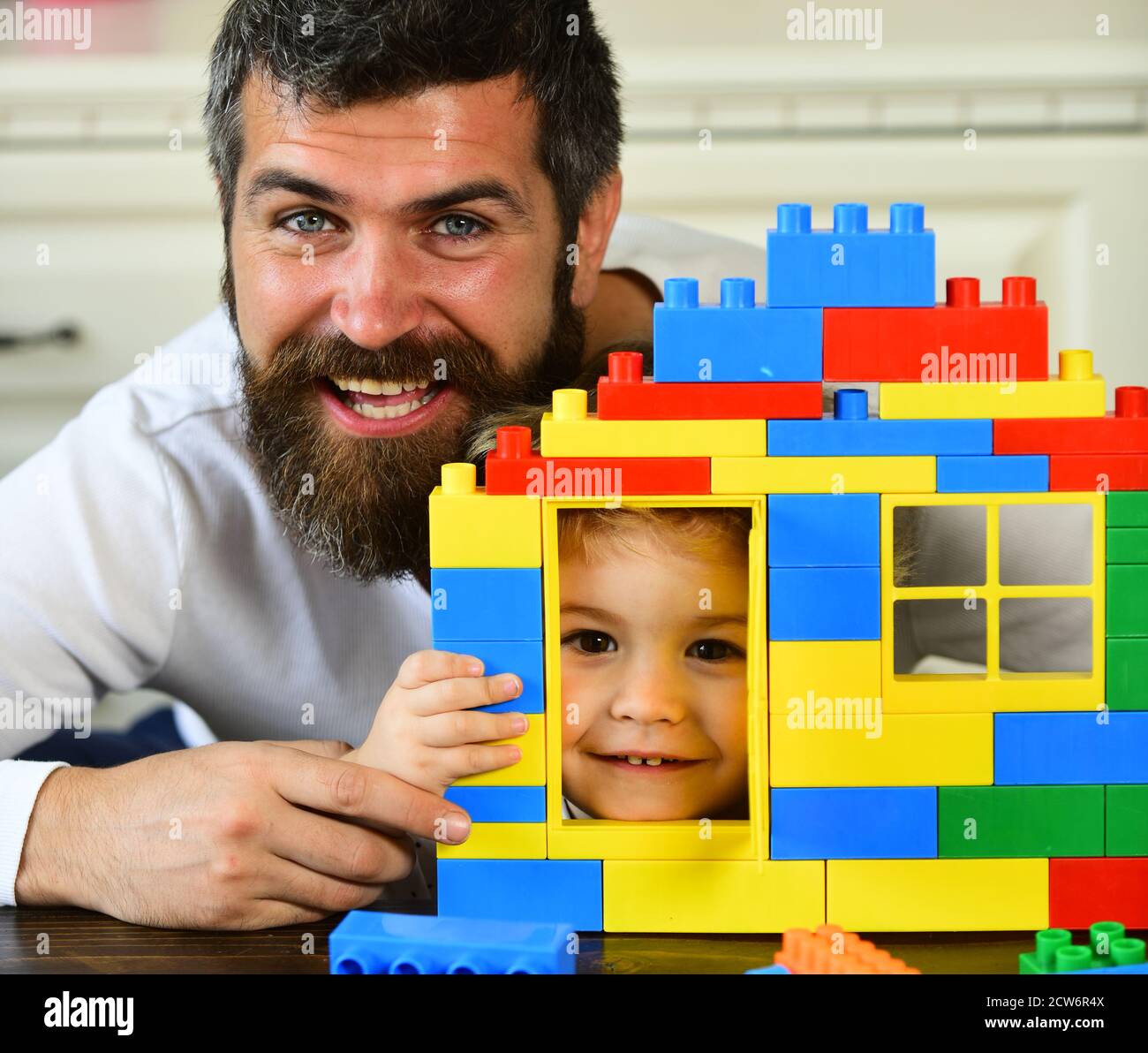 Father and son with smiling faces hold colorful toy bricks construction ...