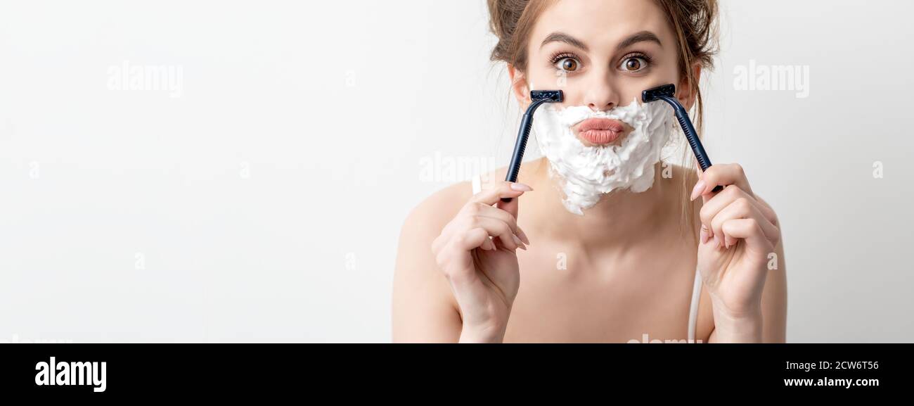 Beautiful young caucasian woman shaving her face by two razors on white ...