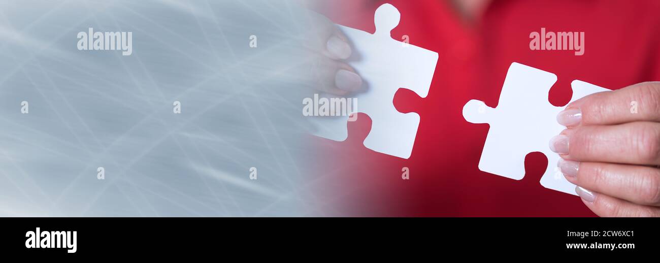 Hands joining two puzzle pieces, teamwork concept; panoramic banner ...