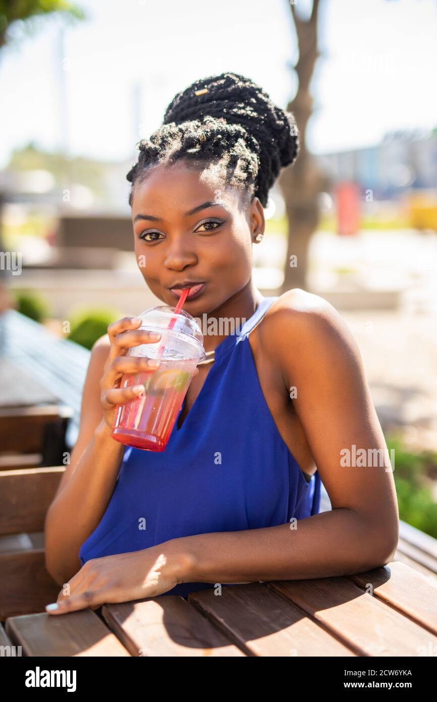 Portrait of happy young african woman having a fresh fruit juice. Young ...