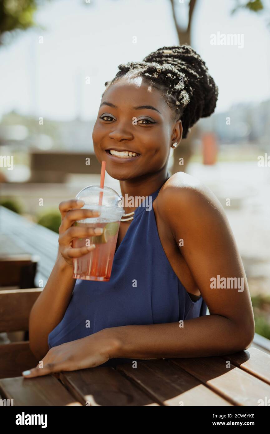 Portrait of happy young african woman having a fresh fruit juice. Young ...